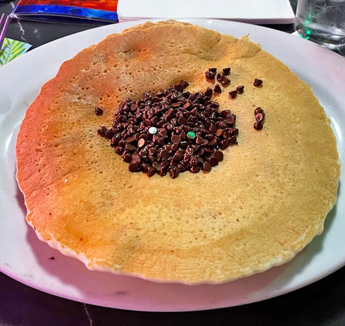 This pancake is so enormous it needs its own area code, with chocolate chips clustered in the middle like a sweet bullseye of morning joy.