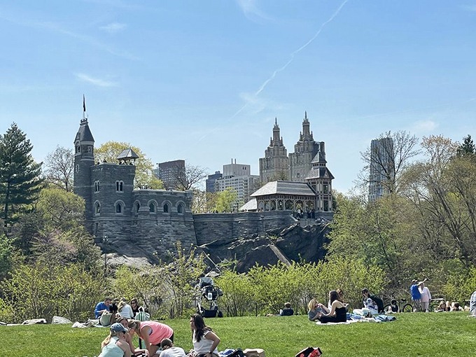 A castle with a view. Visitors relax on the lawn below, enjoying the perfect picnic spot with Belvedere Castle standing guard above.