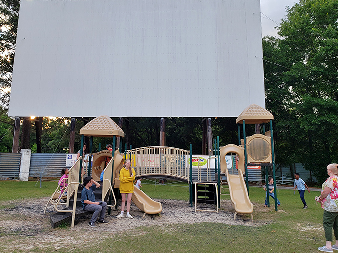 Kids burn off pre-movie energy on the playground while parents set up camp chairs, a perfect symbiotic relationship of drive-in culture.