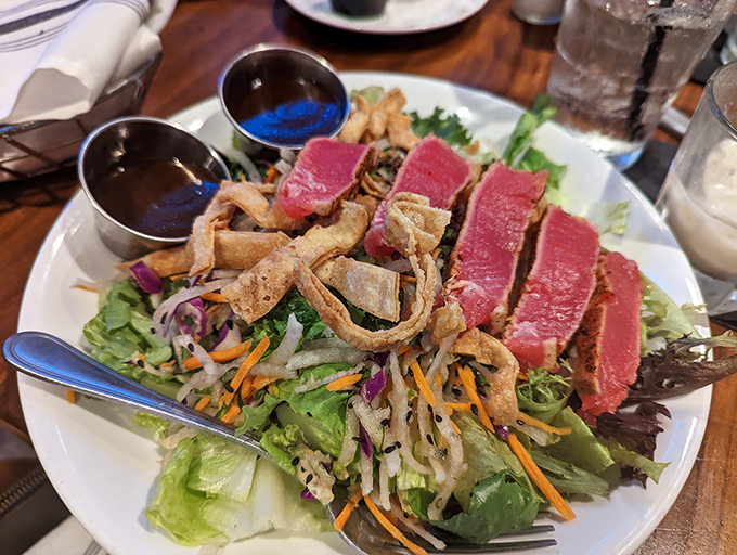 Seared ahi tuna salad &ndash; where health food meets vacation indulgence, with crispy wonton strips providing the perfect textural plot twist.
