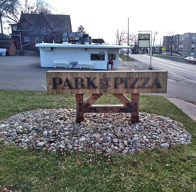 The rustic wooden sign stands like a sentry, promising pizza paradise just beyond&mdash;a beacon for hungry travelers in Sugarcreek.