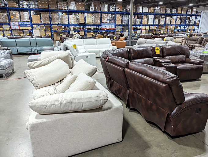 Sofa showdown: cream comfort versus brown leather luxury. The yellow tags whisper promises of prices that make redecorating suddenly seem like a reasonable Tuesday activity.