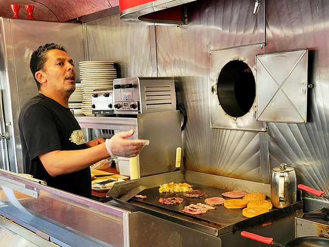 A cook works his magic on the flattop grill, where eggs and pancakes have sizzled under the same skilled hands that make strangers feel like regulars.