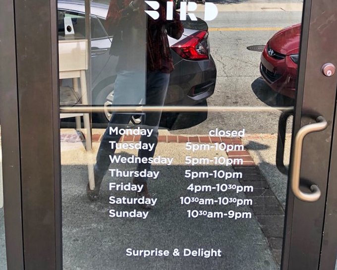 The door promises "Surprise & Delight" beneath the hours&mdash;perhaps the most honest advertising you'll ever see on a restaurant entrance.