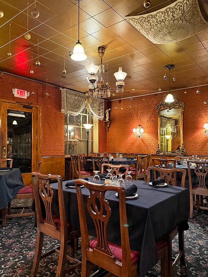 Dining room elegance with ornate wallpaper, vintage lighting fixtures, and wooden chairs that have supported countless celebrations, first dates, and "I'm sorry" dinners.