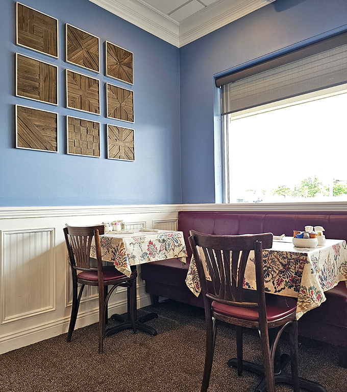 Corner booth seating with those floral tablecloths and wooden wall art&mdash;it's like someone designed a restaurant based on "comfortable breakfast vibes" Pinterest board.