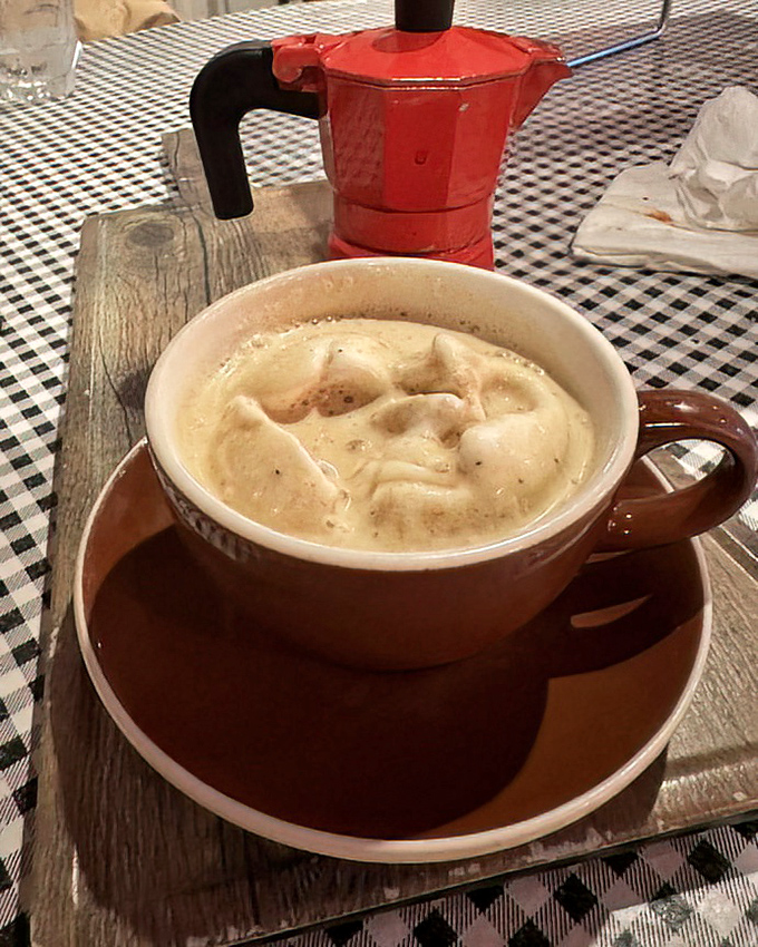 Coffee served with Italian reverence. That little red espresso maker in the background is basically a religious icon here.