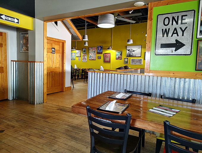 Wooden tables bathed in natural light, corrugated metal accents, and that "One Way" sign pointing toward more BBQ&mdash;they know what you're really here for.