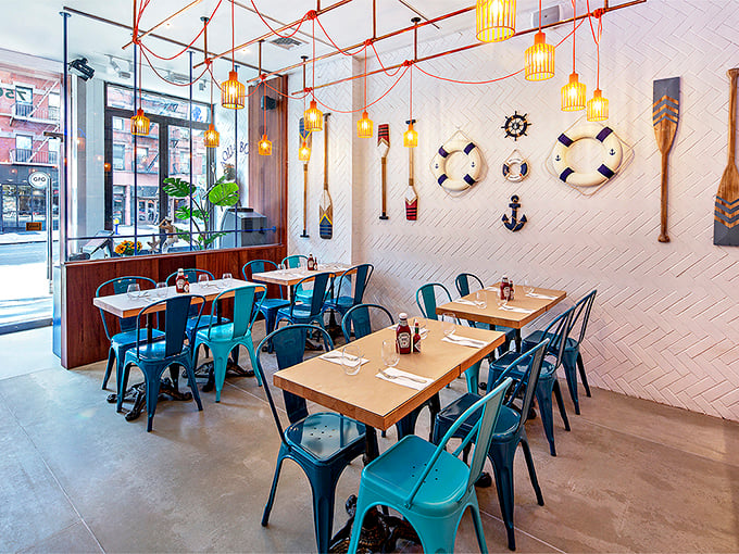 Nautical touches like life preservers and oars adorn white herringbone walls, creating a space that feels like a stylish captain's quarters.