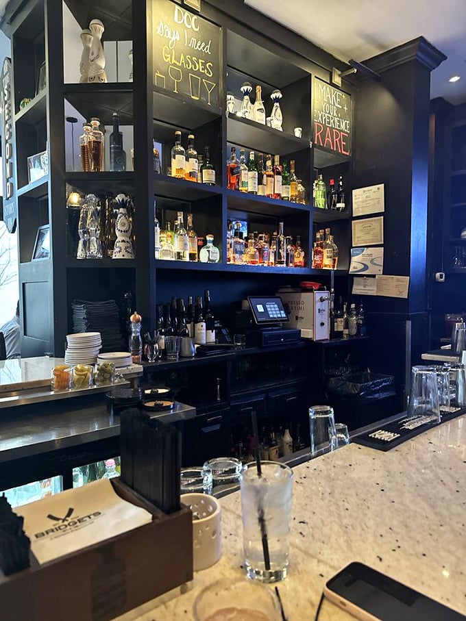 A bar stocked with liquid treasures and clever signage. "You need glasses" isn't just advice&mdash;it's an invitation to explore.