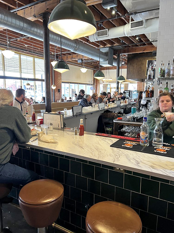 The marble bar countertop invites elbows and stories, while green subway tiles add a splash of vintage diner authenticity.