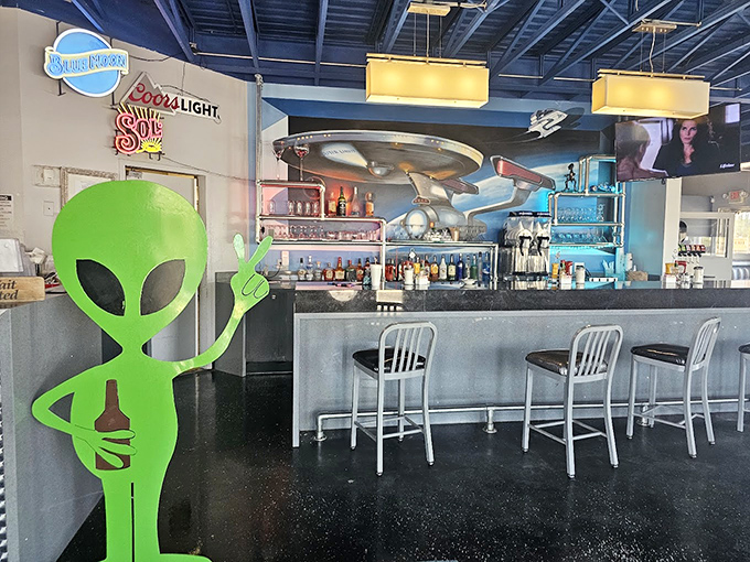 The bar area, complete with alien greeter, serves up cosmic cocktails under a UFO light fixture. Even extraterrestrials need a good happy hour.