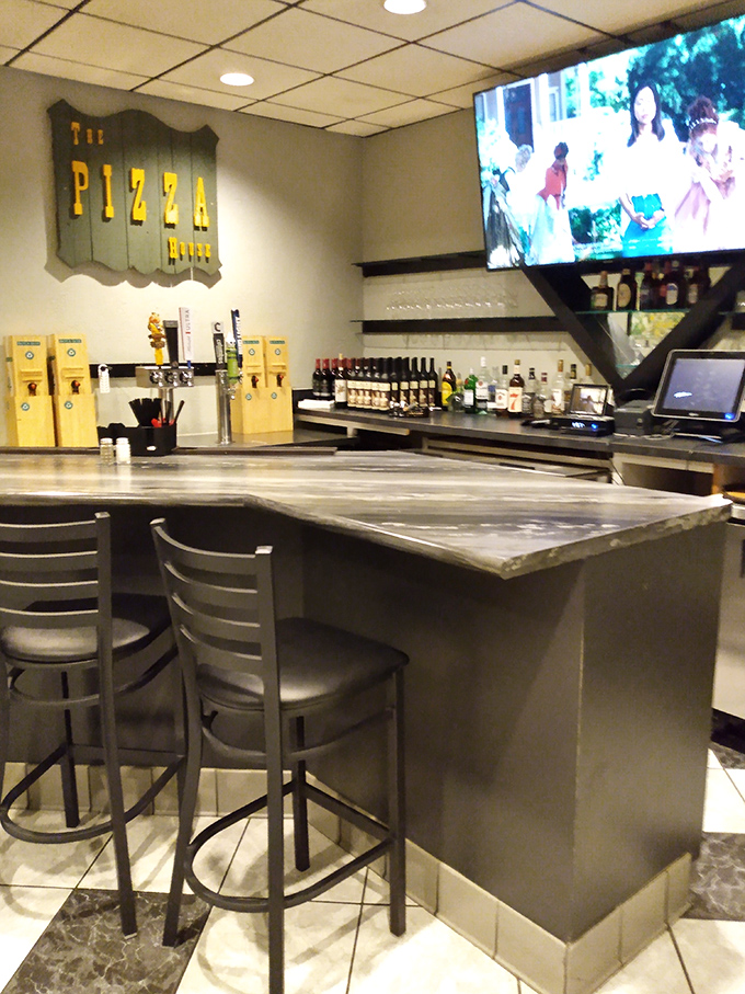 The bar area offers a front-row seat to pizza perfection, where cold drinks and hot pies create the ultimate comfort food experience.