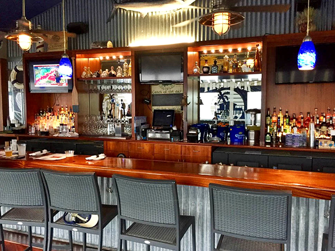 The bar's warm wood tones and industrial metal accents create the perfect perch for sipping something cold while waiting for something hot.