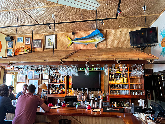 The bar showcases an impressive lineup of rums and spirits, all standing at attention beneath a ceiling of woven matting and colorful fish.