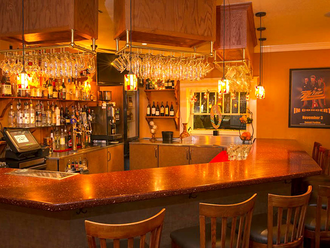 Evening ambiance transforms the bar area into a golden-hued retreat, where wine glasses hang like delicate crystal chandeliers above the counter.