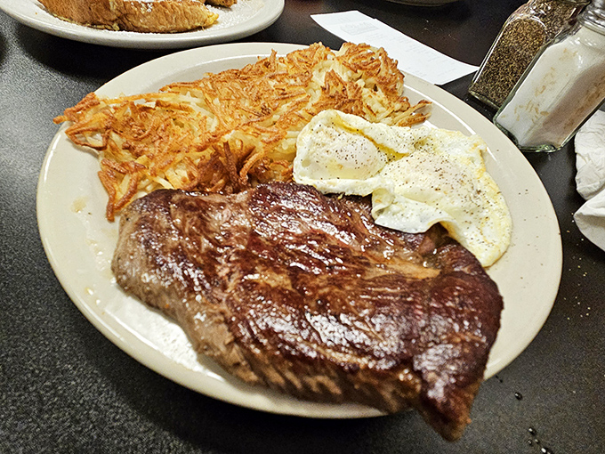 A hearty breakfast plate featuring a perfectly cooked steak, eggs, and those legendary hash browns&mdash;the kind of meal that fuels cowboys and office workers alike.