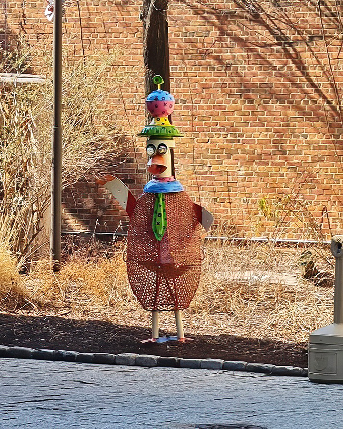 This whimsical chicken sculpture stands sentinel outside, a colorful guardian with a tie that suggests he means serious business.