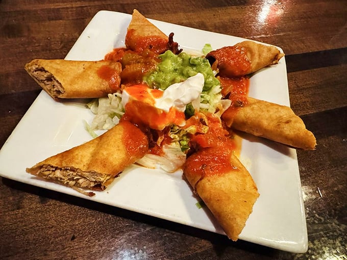 Crispy taquitos arranged like golden logs, drizzled with sauce and ready to disappear faster than your weekend plans.