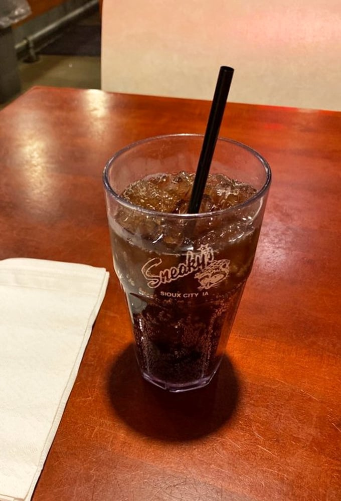 A frosty soda in a Sneaky's branded glass &ndash; because every great fried chicken feast deserves its perfect bubbly companion.