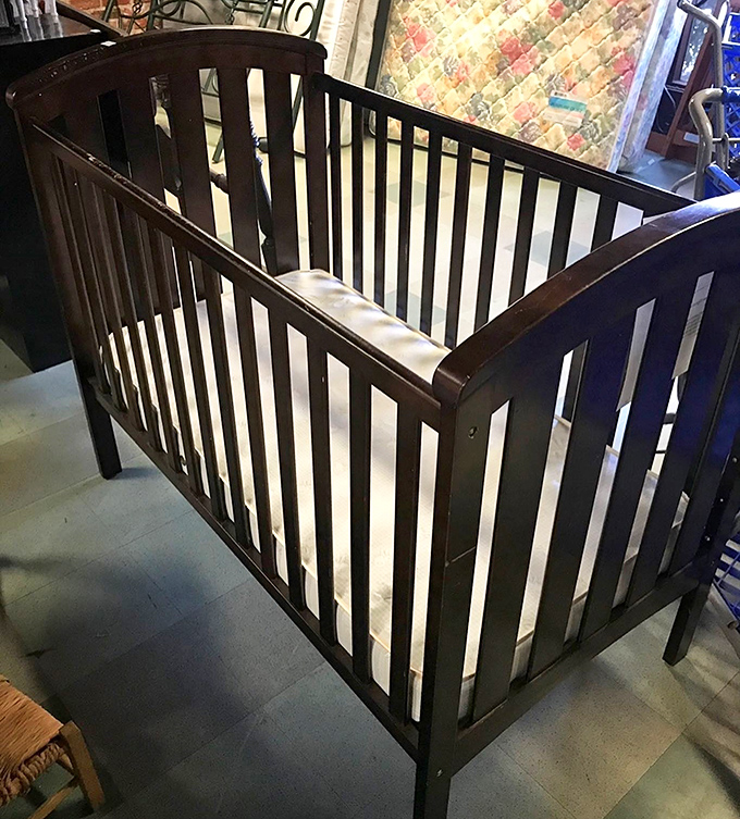 This sturdy crib awaits its next tiny occupant. One family's outgrown nursery item becomes another's first baby nest.