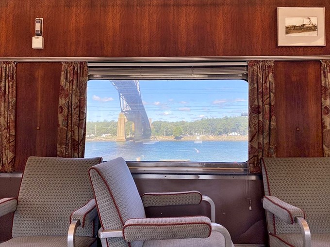 Window seats that frame postcard-worthy moments. The vintage wood paneling and period-appropriate curtains create the perfect frame for the Cape Cod Canal Bridge passing by outside.