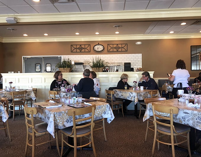 Regulars gather at tables covered in floral tablecloths, participating in the timeless ritual of solving world problems over coffee.