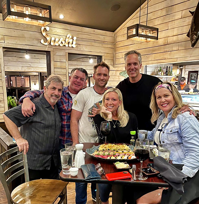 Happy diners celebrating with a sushi feast fit for royalty. The smiles say everything about the meal that's about to disappear.