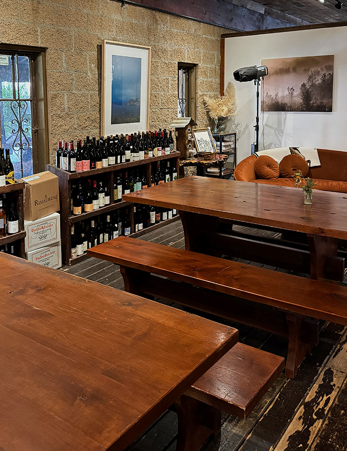 Communal tables aren't just furniture&mdash;they're conversation starters. Wine bottles line the walls like old friends waiting to join your meal.