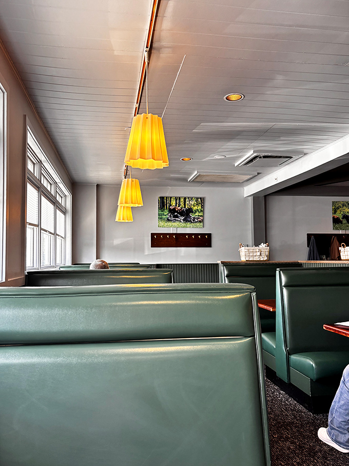Yellow pendant lights hang over green booths like modern farmhouse chandeliers, proving comfort and style aren't mutually exclusive concepts.