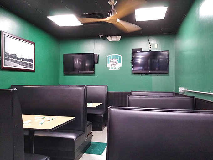 Dark booth seating and bright green walls create visual interest while TVs keep sports fans happy between burger bites.