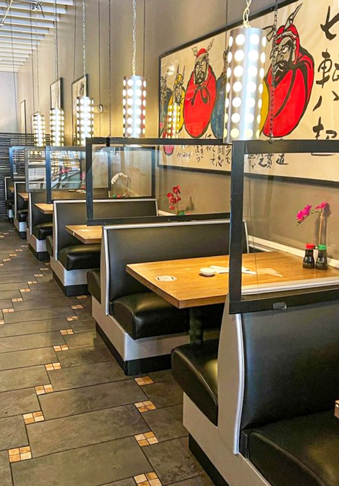 Booth seating with traditional artwork creates dining pockets of privacy, while cylindrical lights cast a warm, inviting glow.