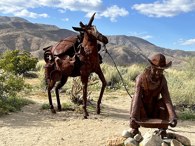 A prospector and his faithful companion pause on their eternal journey, metal figures telling tales of California's gold rush past.