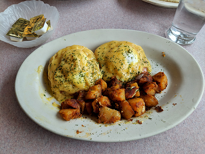 Eggs Benedict done right—two golden-yolked poached eggs perched atop their throne, draped in hollandaise that glistens like morning sunshine.