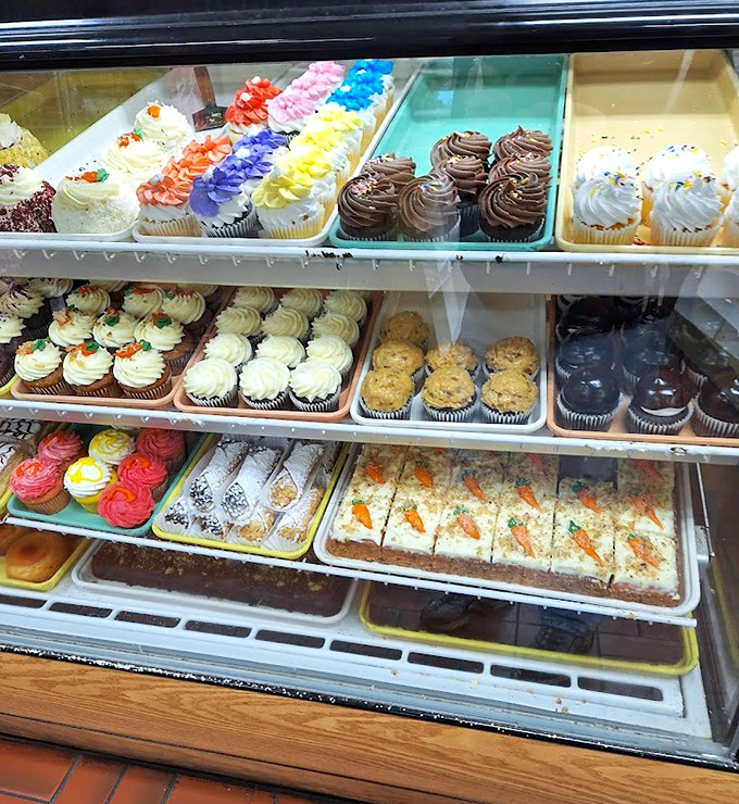 Cupcakes in every color of the rainbow stand at attention, their frosting swirled higher than a 1960s beehive hairdo.