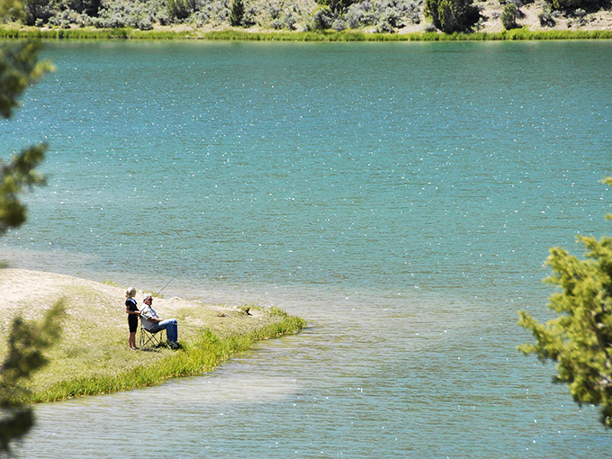 Two anglers finding their zen at water's edge. Fish stories optional, but that tranquil turquoise backdrop is guaranteed.