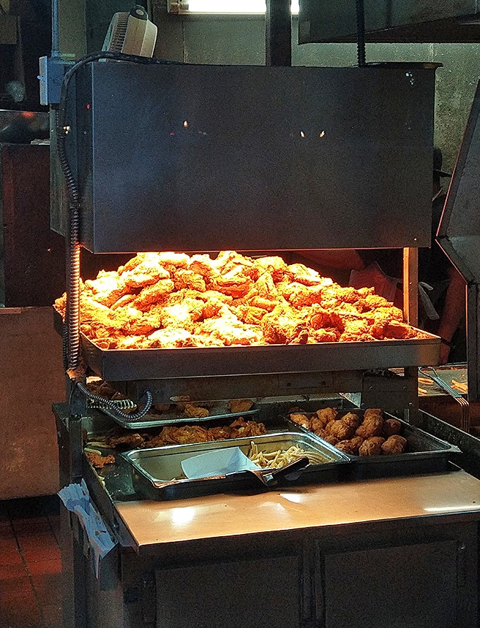 Mountains of freshly fried chicken resting under warmers, waiting to make someone's day exponentially better with every crispy bite.