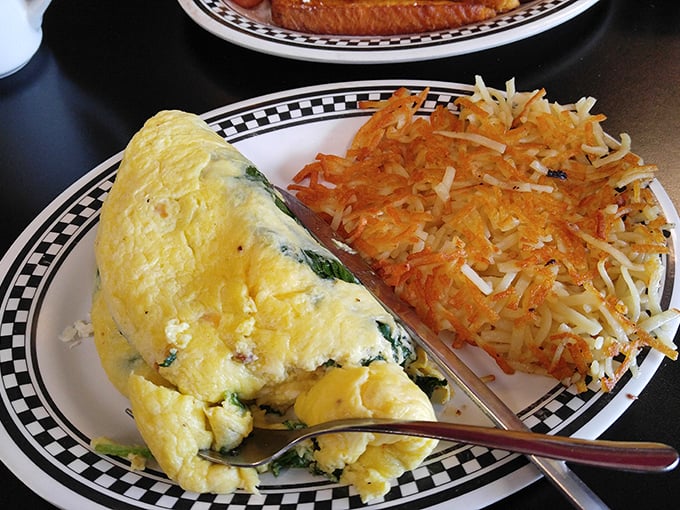 An omelet that's clearly been to the gym&mdash;buff, yellow, and proudly showing off its veggie gains next to crispy hash browns.