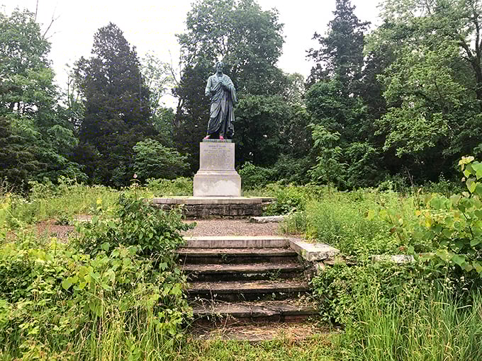 The Horace Mann monument stands in quiet dignity, surrounded by nature's slow reclamation. History and wilderness find balance in this contemplative spot.