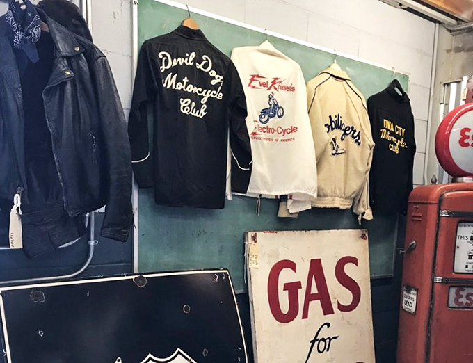 Vintage motorcycle club jackets hang like leather-bound history books, each patch and emblem telling stories of open roads and brotherhood.