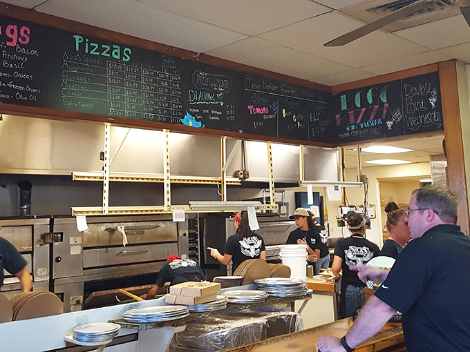 Behind the scenes, the kitchen crew orchestrates pizza perfection beneath a chalkboard menu that promises delicious possibilities.