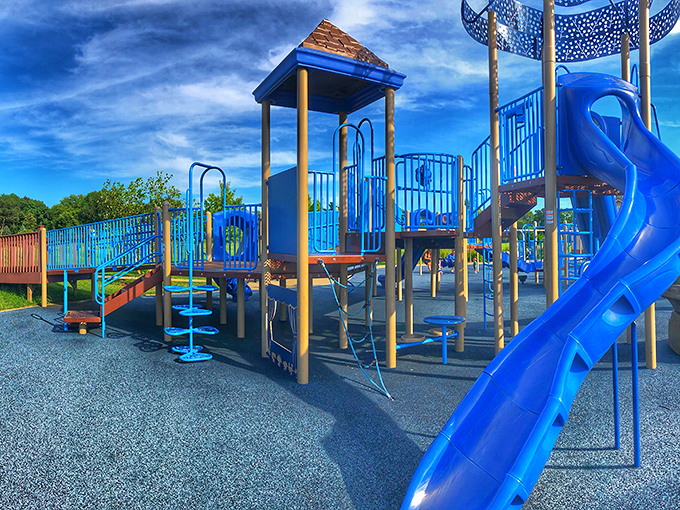 This playground's blue slides and climbing structures stand ready to transform ordinary afternoons into adventures worthy of childhood memory highlight reels.