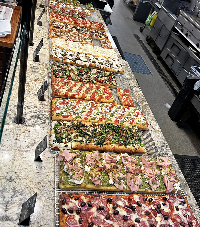 Pizza display that stretches toward the horizon. Each variety tells a different story of Italian regional traditions, all available by the slice.