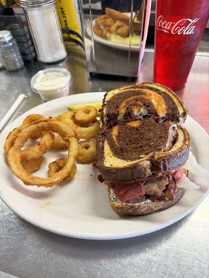 This Reuben sandwich with golden onion rings isn't just lunch &ndash; it's an architectural achievement. The marble rye swirl adds both style and substance.