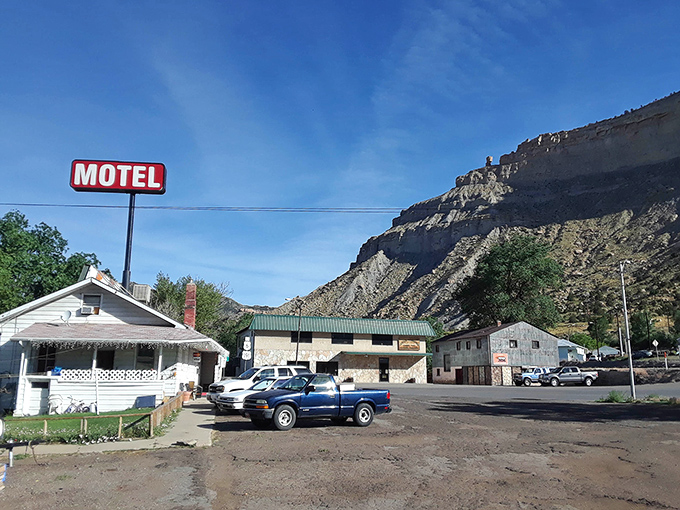 The Riverside Motel sign stands like a sentinel against those dramatic cliffs, promising weary travelers a bed with a view that beats any five-star city hotel.