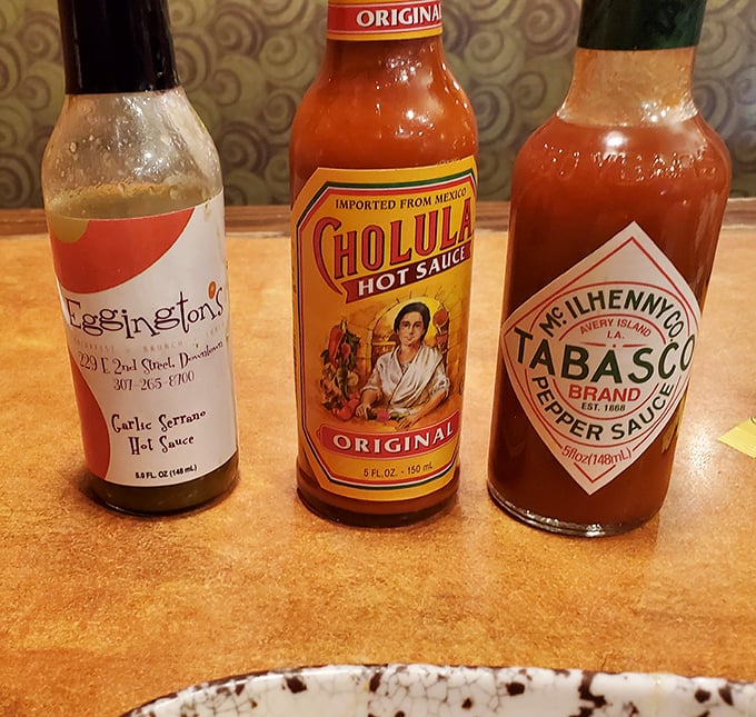 The hot sauce trinity: where Eggington's house-made Garlic Serrano meets its famous cousins. Choose your breakfast adventure wisely.