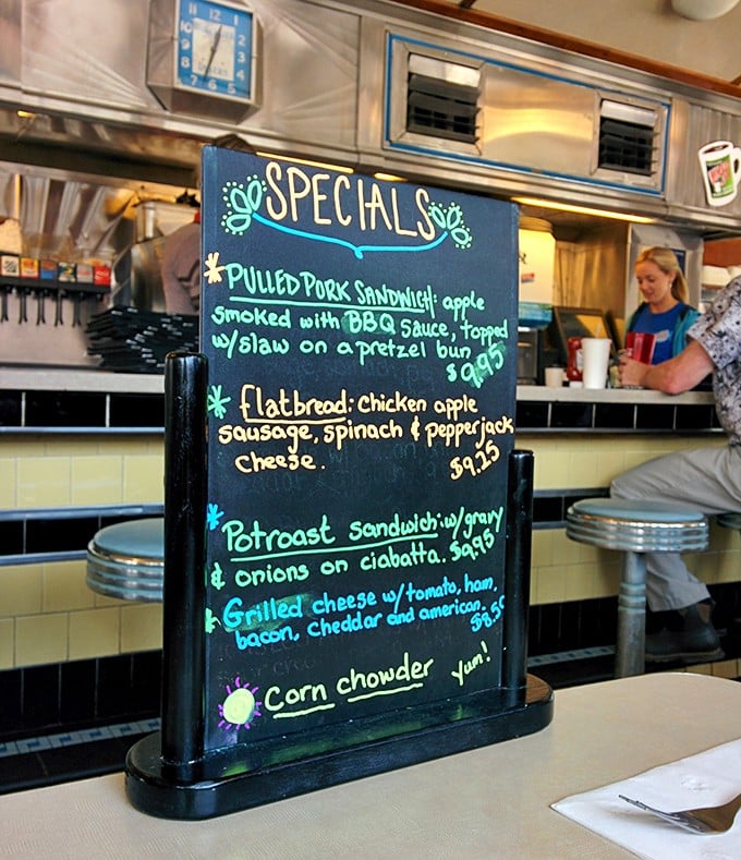The specials board&mdash;where daily inspiration meets chalk artistry. That pulled pork sandwich is practically auditioning for a permanent menu spot.