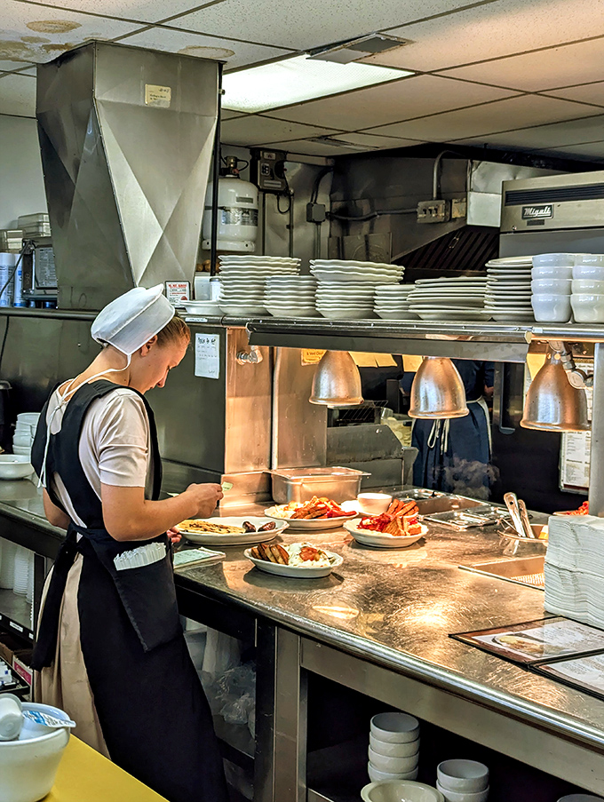An Amish cook in traditional dress plates meals with practiced precision – each dish a testament to generations of culinary wisdom.