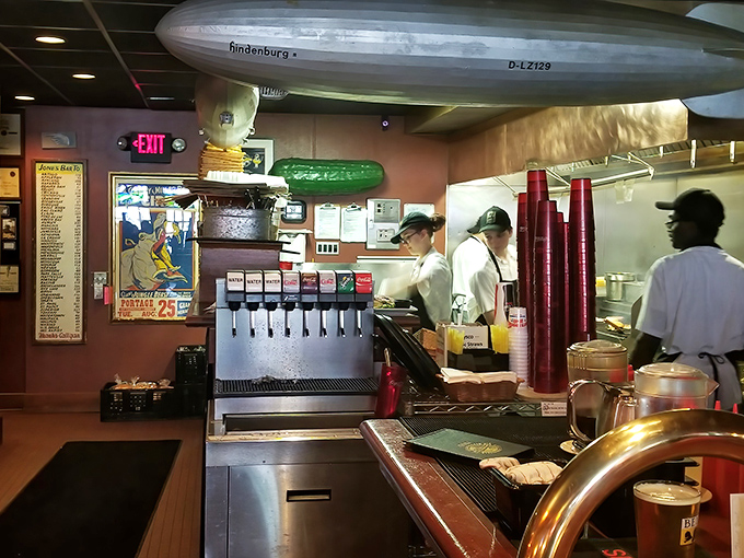 Behind the counter, culinary choreography unfolds beneath a model Hindenburg, proving good food is rarely the result of accidents.