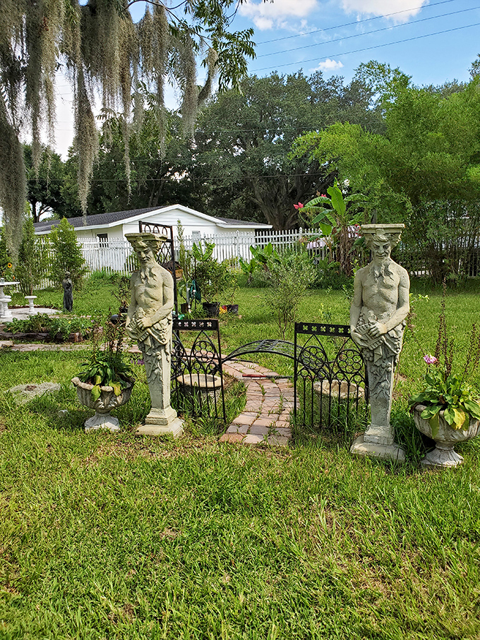 Classical-inspired statues stand sentinel at this garden gate, their stony gazes having witnessed decades of Florida seasons.